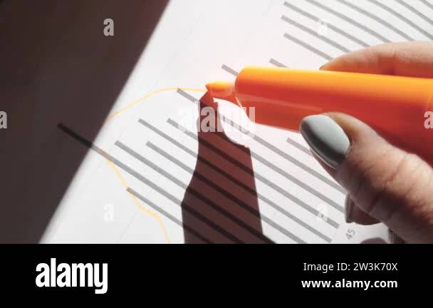 Close-up of a woman drawing a diagram with an orange marker. The female ...