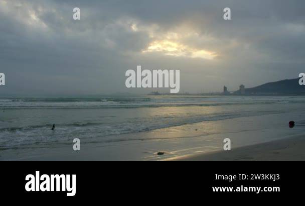 A large sun appears from behind the clouds, and large mountains touch ...