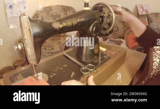 grandmother sews a red flag on an old sewing machine of the Soviet ...