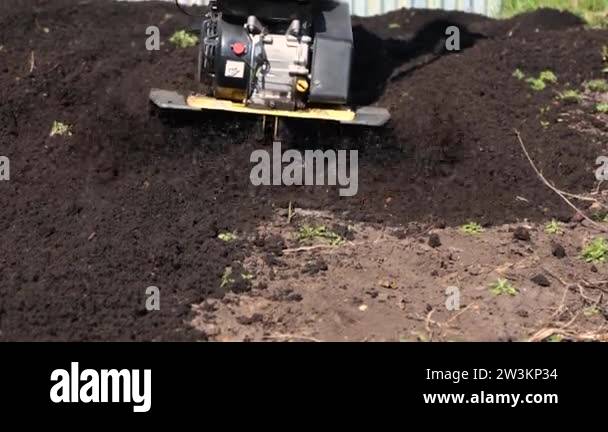 Close up, Man plowing the land in the garden with a cultivator ...