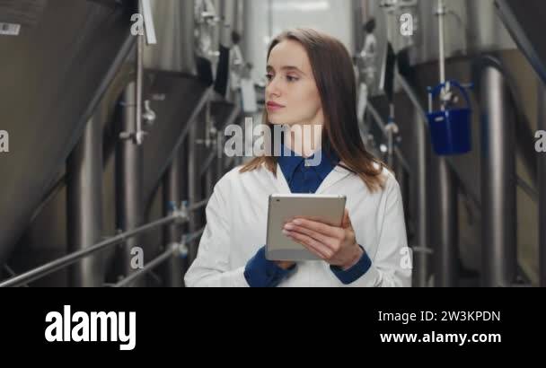 Handsome female process engineer maintaining records on tablet at ...