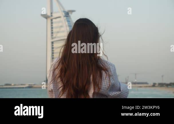 Female tourist pointing at Burj Al Arab hotel in Dubai during sunset ...