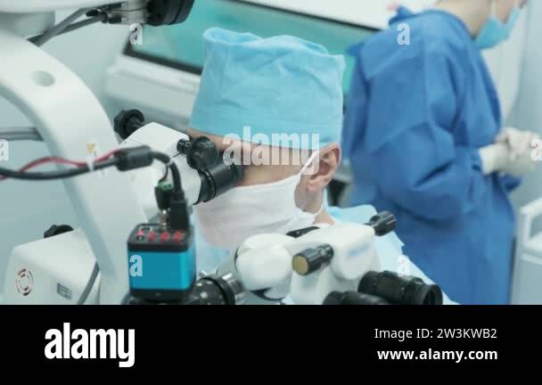 Surgeon looking into the microscope at the eye of female patient at the ...