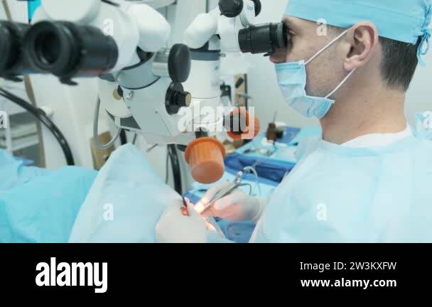 Surgeon looking into the microscope at the eye of female patient at the ...