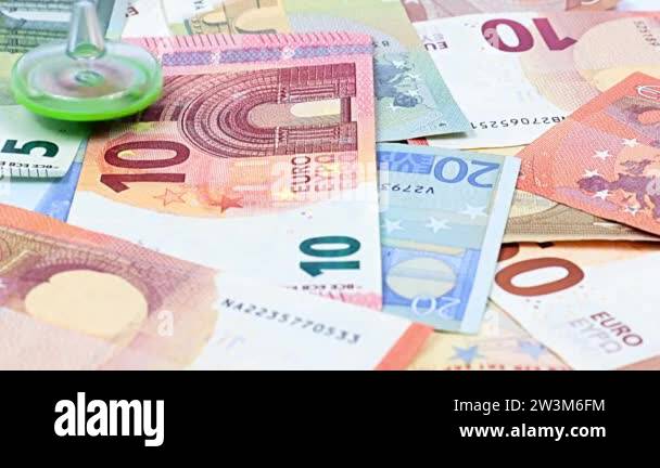 the rotation of a plastic whirligig on a pile of euro banknotes as a ...