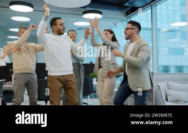 Middle Eastern man dancing at corporate event while colleagues clapping ...