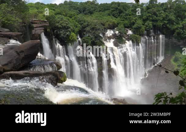 Kalandula Falls spraying water over bushes and tart-like rocks in ...