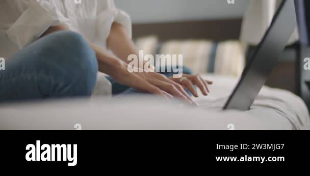 Woman hands typing something on a laptop keyboard in the bedroom. Slow ...