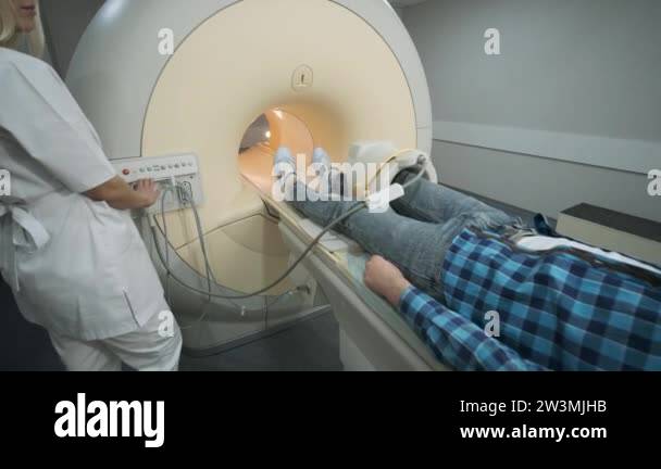 Woman doctor makes knee-joint MRI scanning. Young man patient on ...