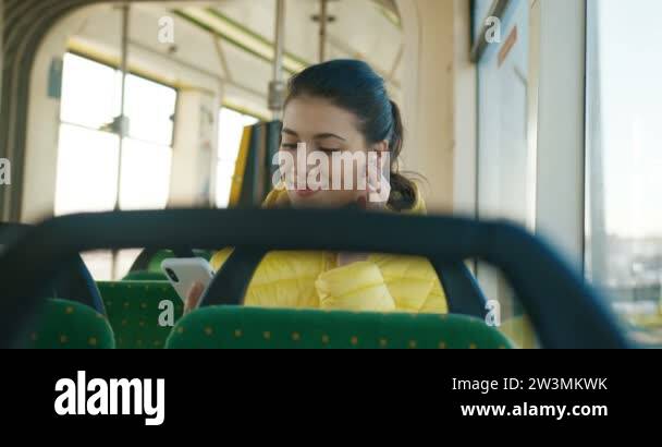 Young stylish Caucasian girl sitting in bus at window and texting ...