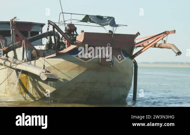 Dredging boat by the riverbank with pipeline system hold with bamboo ...