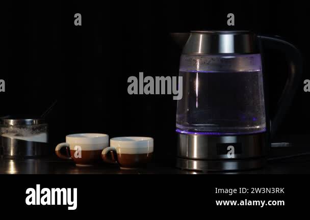 Boiling water in glass transparent electric kettle with blue light ...