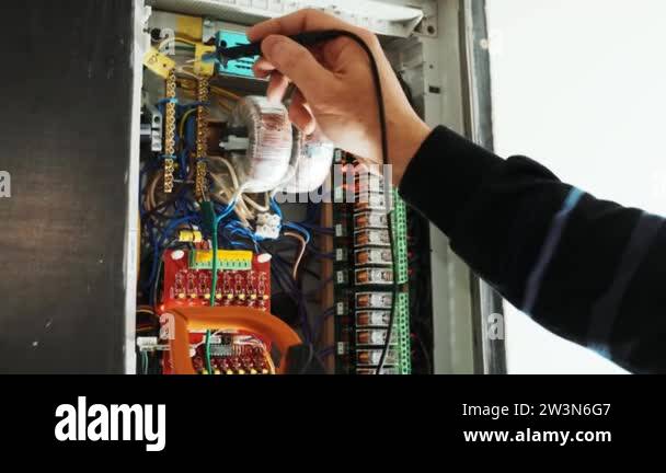 Electricians hands testing current electric in control panel ...