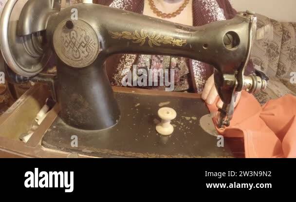 grandmother sews a red flag on an old sewing machine of the Soviet ...