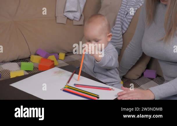 A little daughter enthusiastically drawings with colored pencils on ...