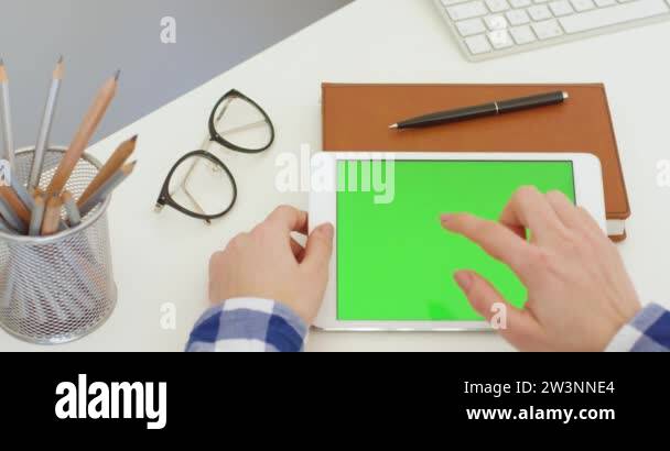 White horizontal tablet device with green screen in hands of Caucasian ...