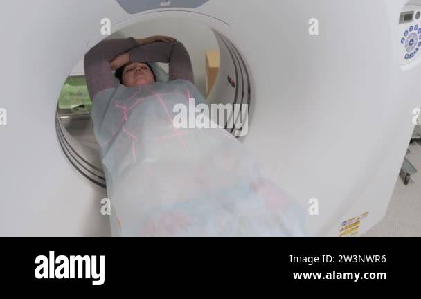 Woman lying on the CT or MRI scanner during machine imaging her body ...
