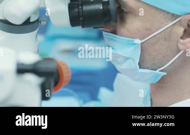 Surgeon looking into the microscope at the eye of female patient at the ...