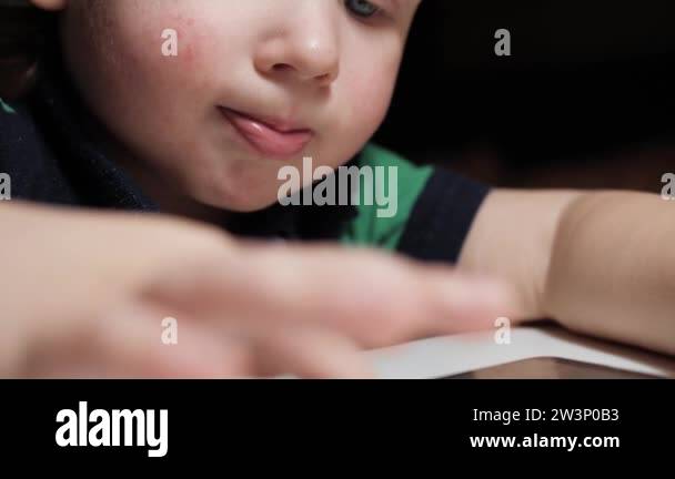 Baby plays with phone. Close-up of face of child who is intently ...