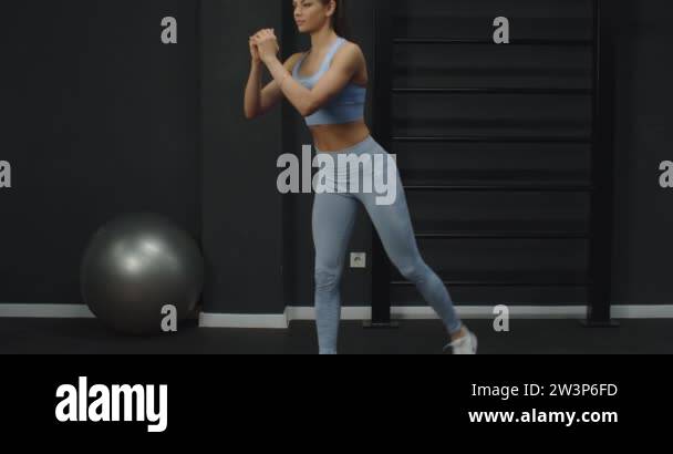 Young slim sportswoman doing squat exercises, working on the lower legs ...