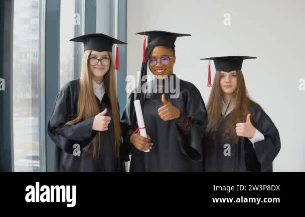 Three female students of different races with a diploma in hand ...