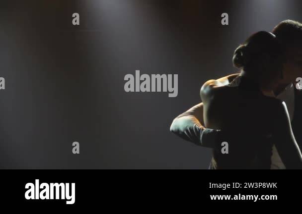 Couple is dancing fast rhythmic tango dance in dark studio with bright ...