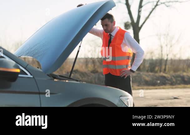 Disappointed man in formal outfit opening bonnet of broke down car to ...
