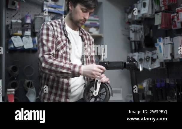 Electric scooter repair workshop. Mechanic holds in his hand broken ...