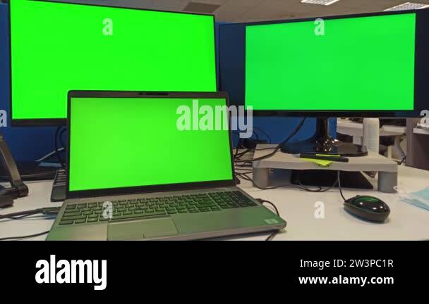 Workstation of 3 computer monitor on desk with green screen in 4k. One ...