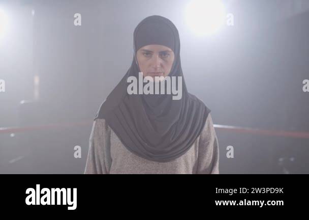 Young confident muslim woman in hijab looking at camera and raising ...