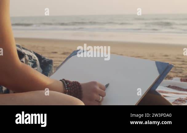 Faceless artist starting drawing outdoors on sandy seaside background ...