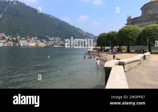 Como, July, 2019 - tourists enjoy the lake of Como on a small beach ...