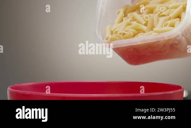 Uncooked raw Italian pasta falling into a bowl, meal preparation by a ...
