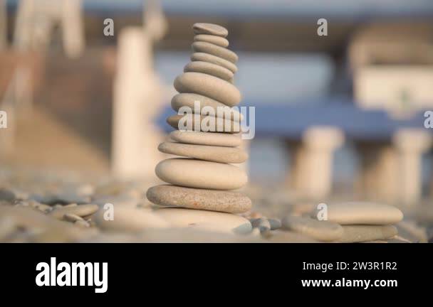 A woman's hand puts stones on the pyramid. The pyramid is collapsing ...