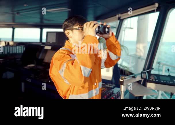 Filipino deck Officer on bridge of vessel or ship looking through ...