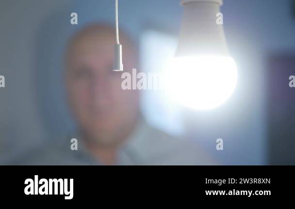 One Person Pull the Switch Cord and Turns Off the Light Bulb in a Room ...