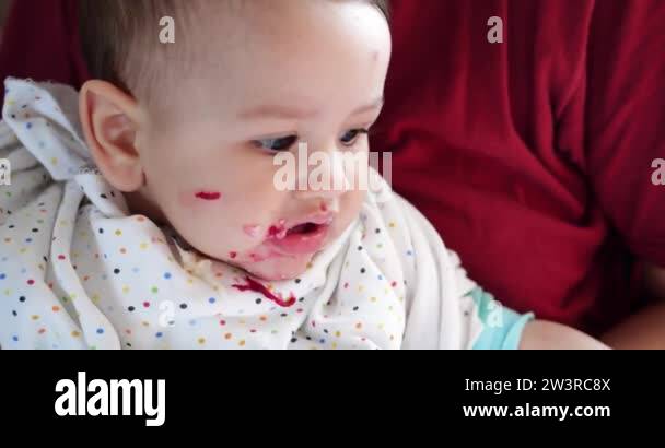 mother holds the baby in her arms and feeds her boy with a spoon ...