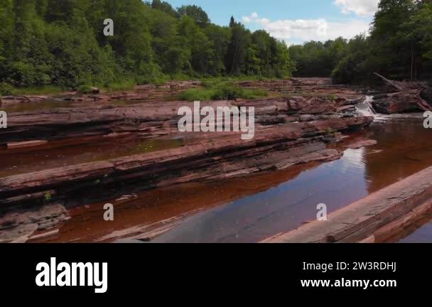 Shallow river with red rocks in the woods. Bonanza falls in Upper ...