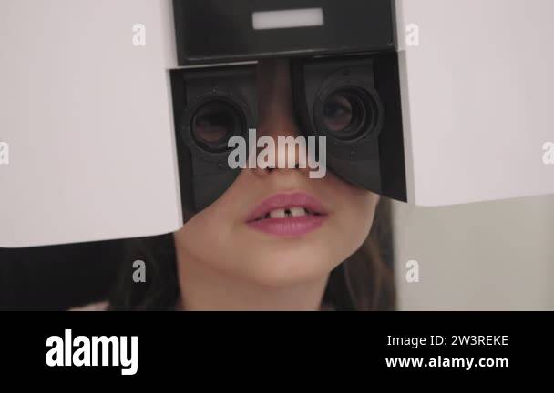 Close-up of little girl sitting in chair at oculist office doing eye ...