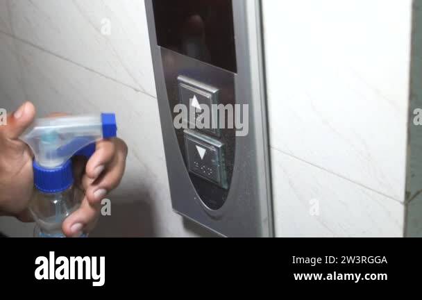 staff hand using wet wipe cleaning an elevator push button control ...