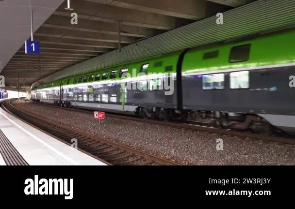 A modern two-tier train departs rapidly gaining speed. Time to travel ...