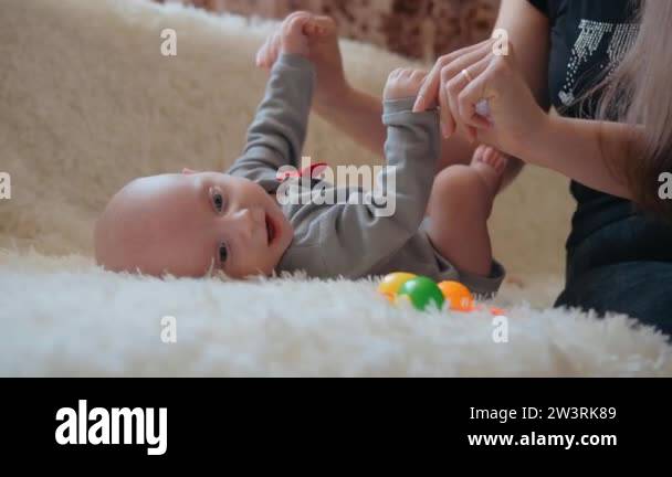 A mother does developmental physical exercises for her newborn baby ...