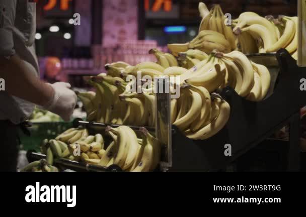 Close-up of a worker in uniform and gloves in a supermarket is sorting ...