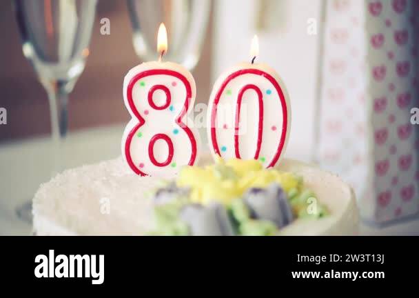 Birthday candle as number eighty 80 on top of sweet cake on the table ...