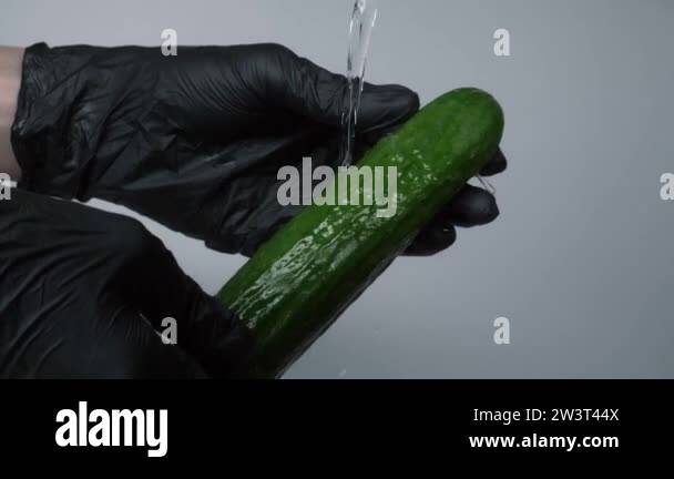 Washing the green cucumber with water splash on grey background, slow ...