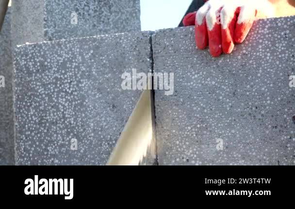 sawing a foam concrete block with a hand saw. The blocks are made of ...