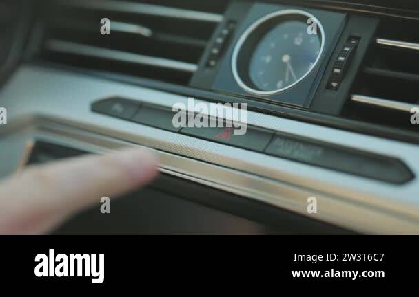 Close-up of male caucasian hand pressing emergency light button on car dashboard. Activating the ...