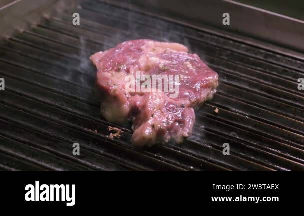 Slow motion view steaks on grill with blazing flame close up view. Chef ...