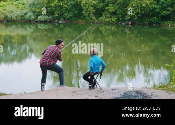 Two brothers on fishing - man pulling the rod and his little brother ...