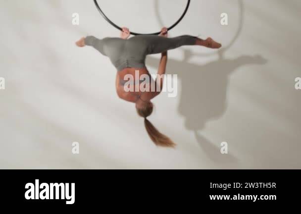 Girl gymnast on an acrobatic ring on a white background with shadows ...